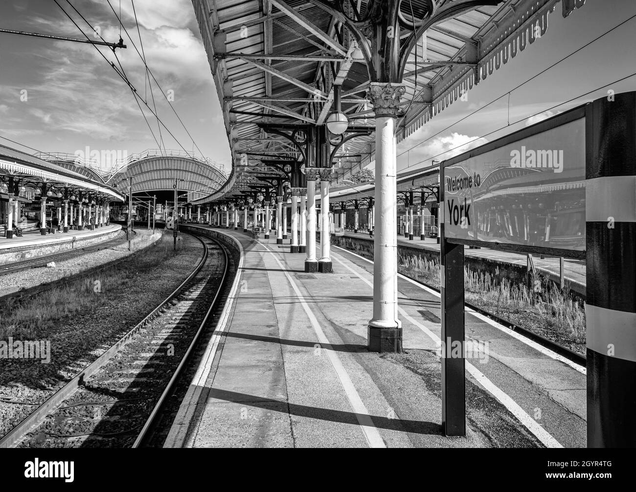 Station welcome sign in blue and white. Shadows fall onto the platform ...