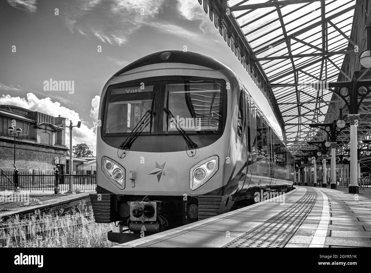 A railway station platform with a train. Columns support the historic ...