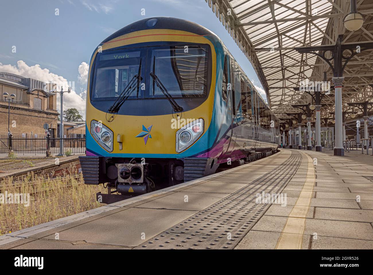 A railway station platform with a train. Columns support the historic ...