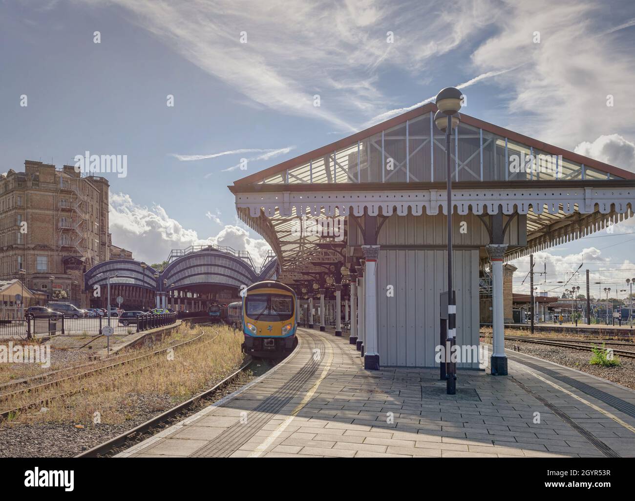 A railway station platform with a train. Columns support the historic ...