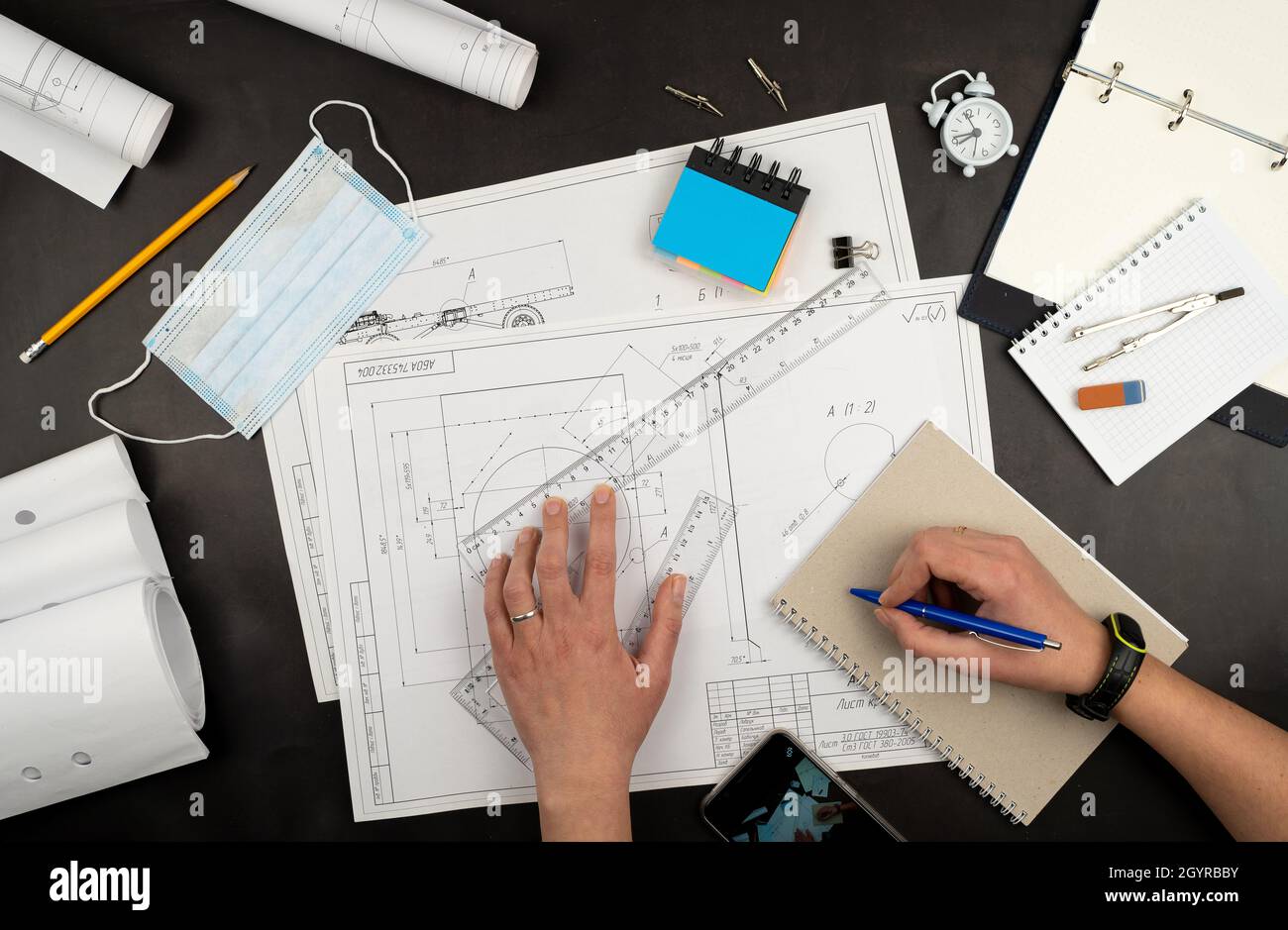 Mechanical drawing on sheets of paper. Hands on the table top view ...