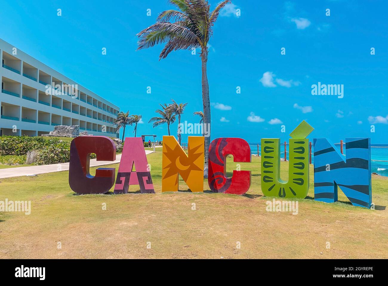 Cancun name sign at park against tree and sea by hotel Stock Photo - Alamy