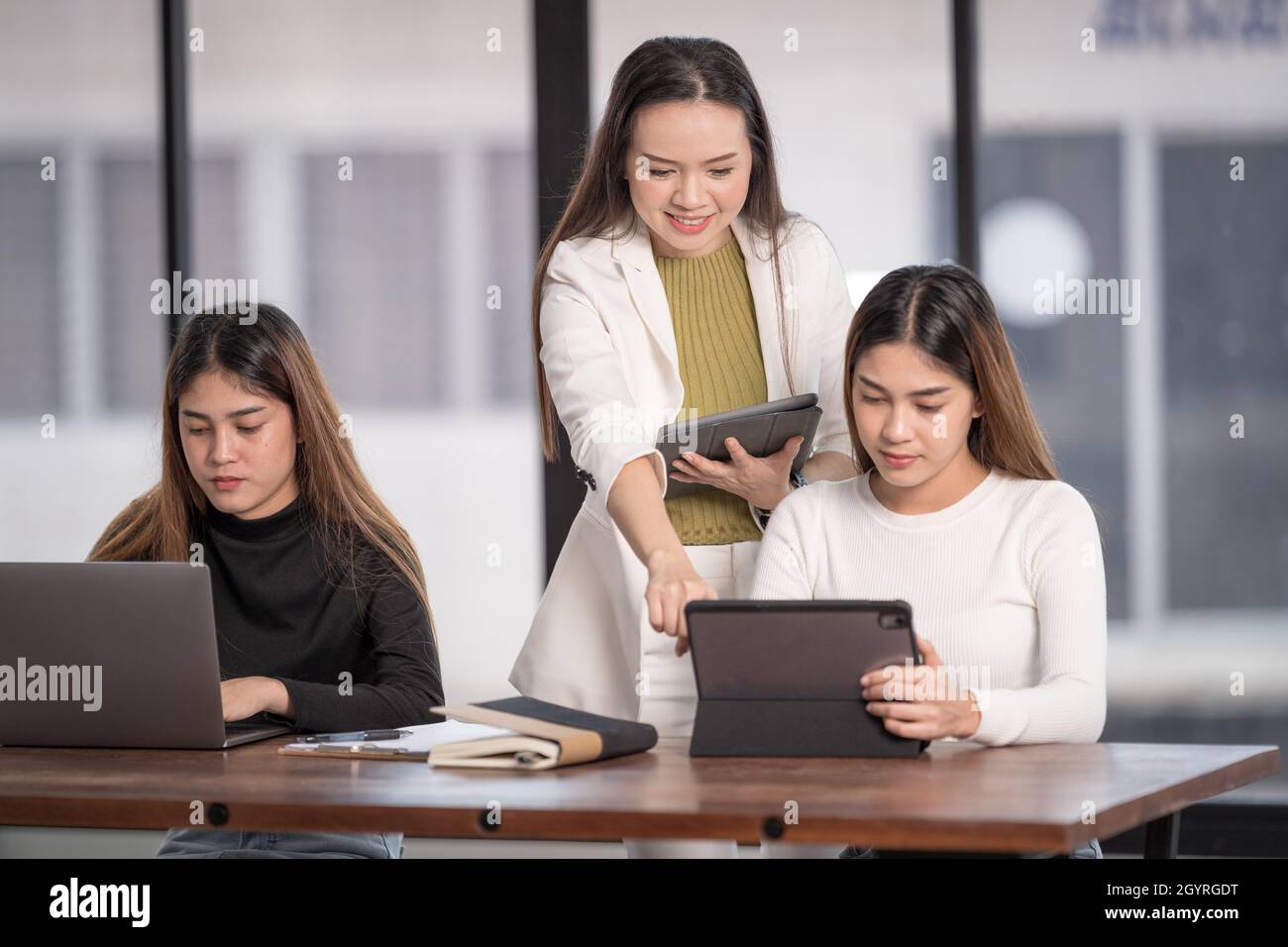 Horizontal shot of Asian females meeting with their tutor working with ...