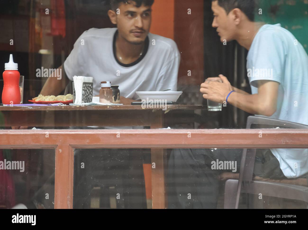 View of people eating food in the cafe seen through the window glass ...
