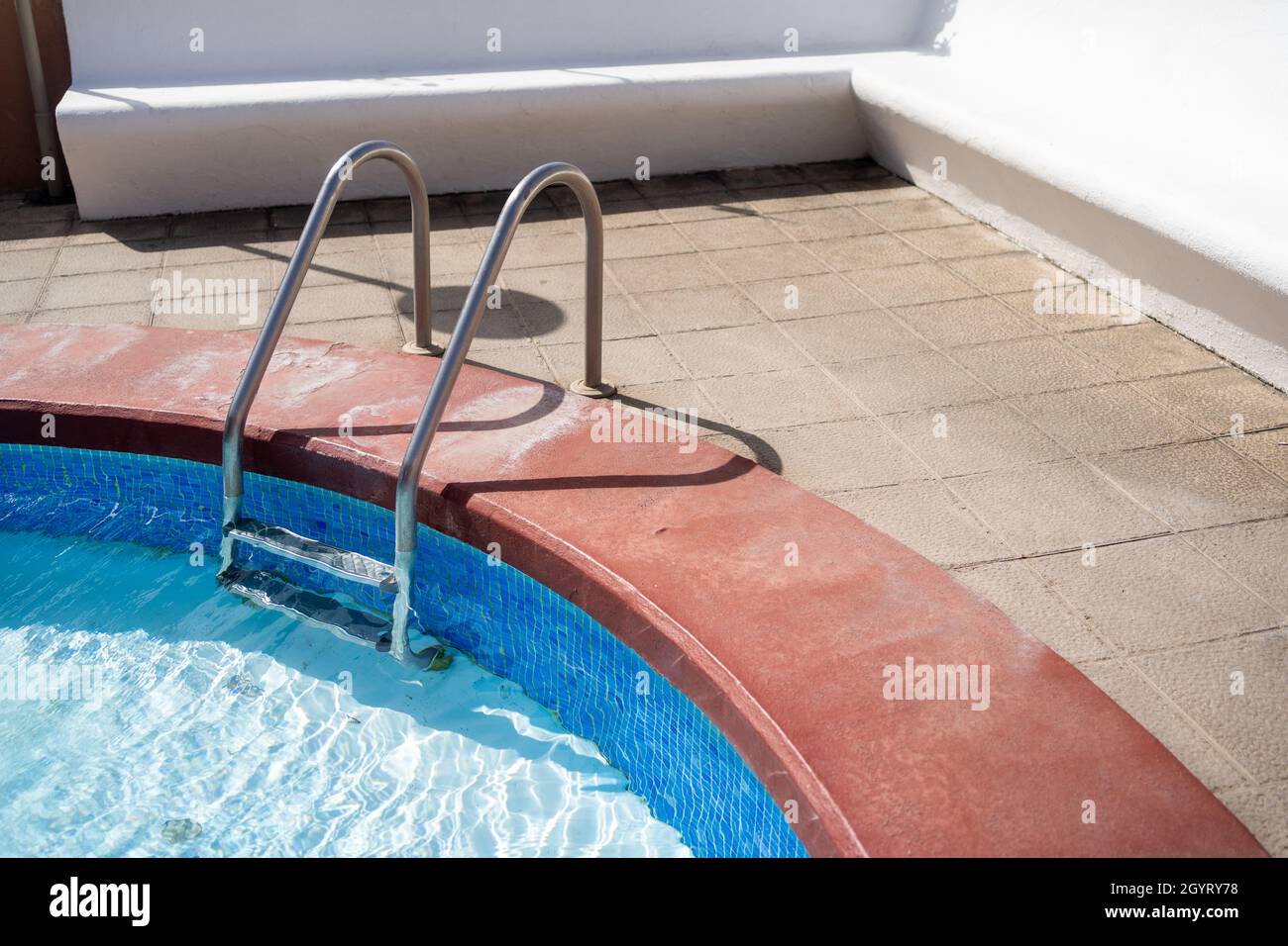 Silver ladder leading into a pool in a garden Stock Photo - Alamy