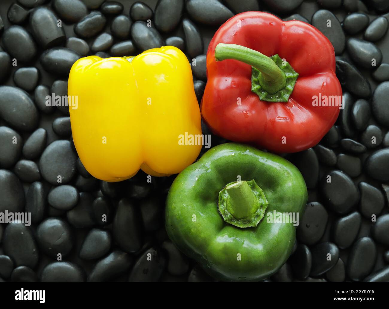 Red, green and yellow bell peppers on blackstone that has smooth glossy ...