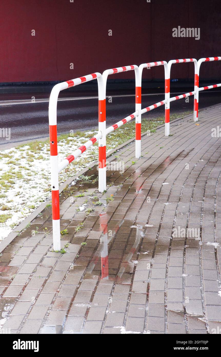 Red and white barrier next to a sidewalk Stock Photo - Alamy