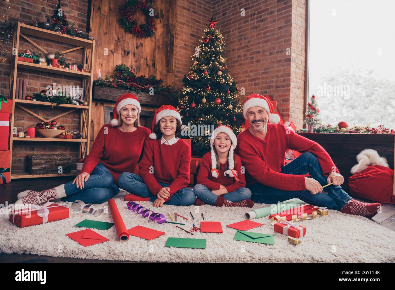Portrait of beautiful handsome cheerful family sitting on carpet making ...