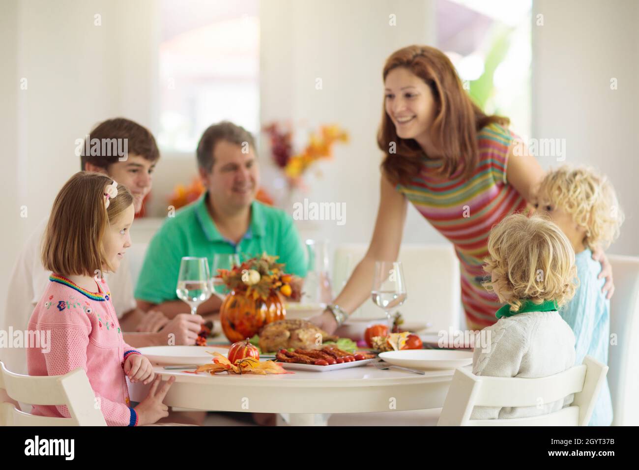 Family with kids eating Thanksgiving dinner. Roasted turkey and pumpkin ...