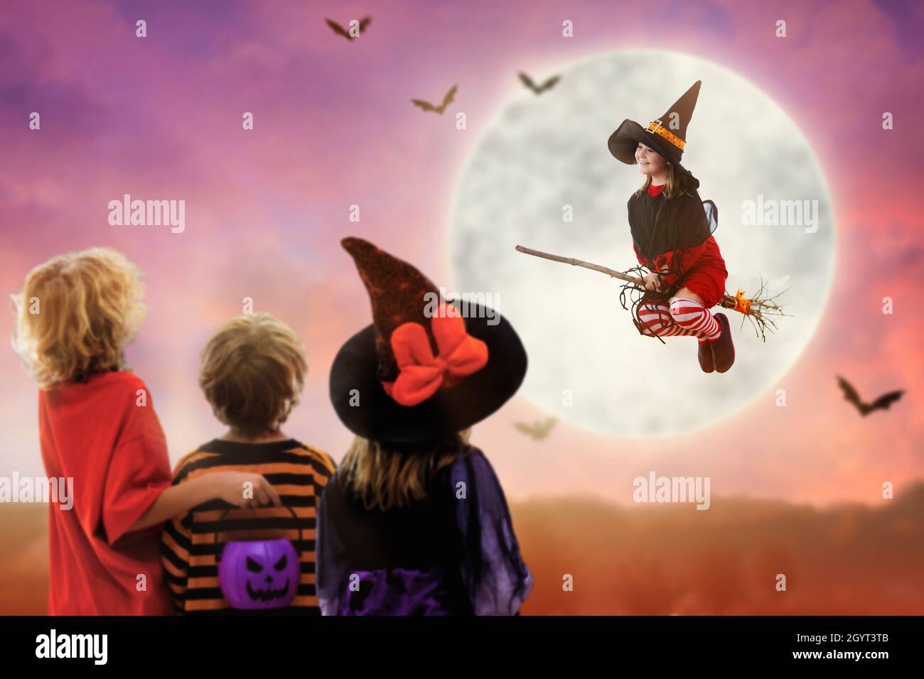 Little witch flying broom on Halloween night. Kids watch huge full moon ...