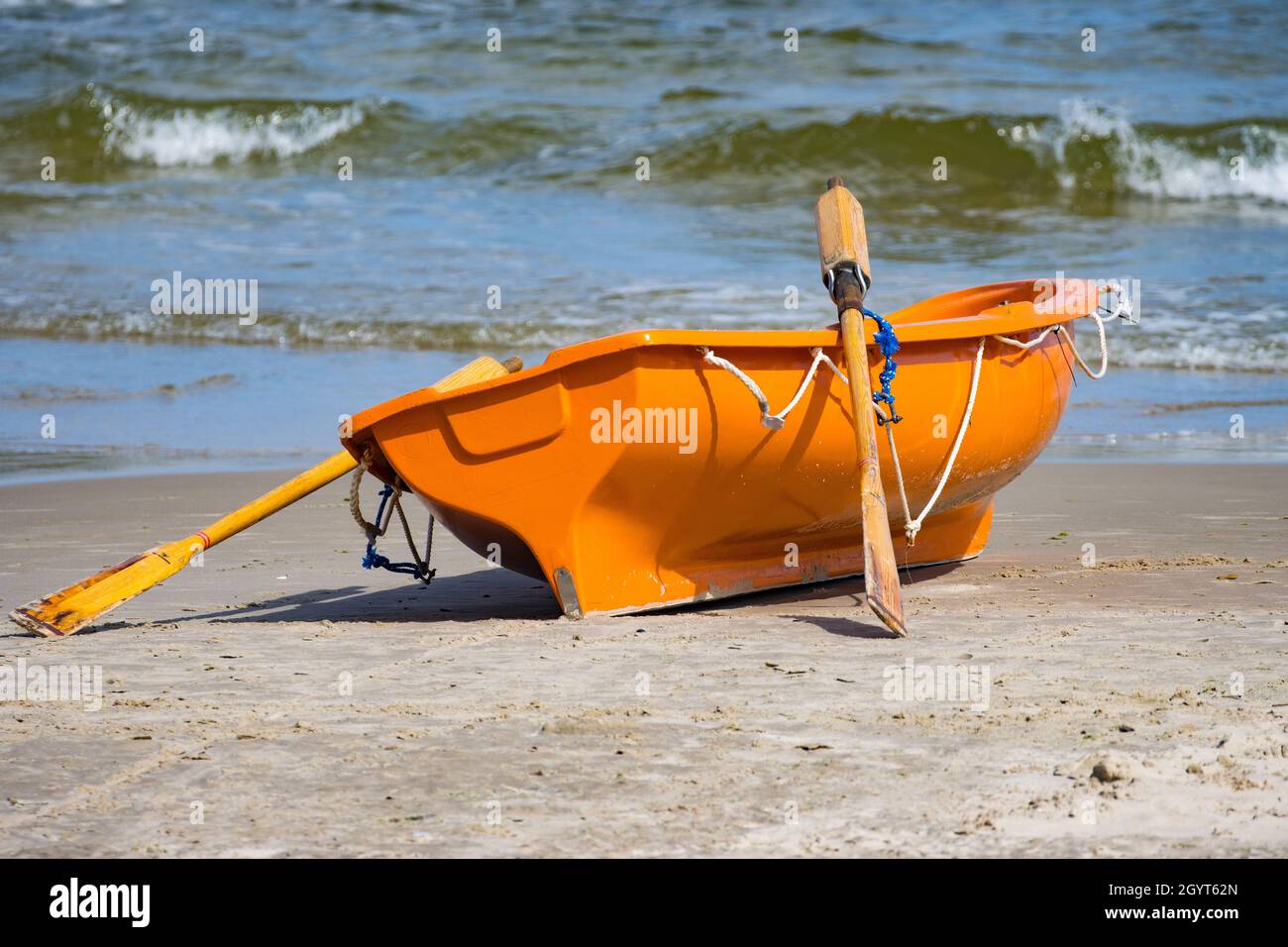 Shot of an orange boat at the beach with the background of waves Stock ...