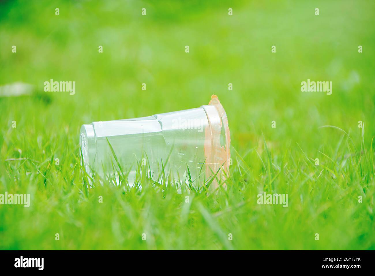 Closeup clear plastic cup garbage recycles on the green grass field in ...