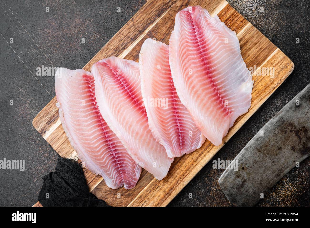 Raw tilapia fish fillet meat cuts, on old rustic background, top view ...