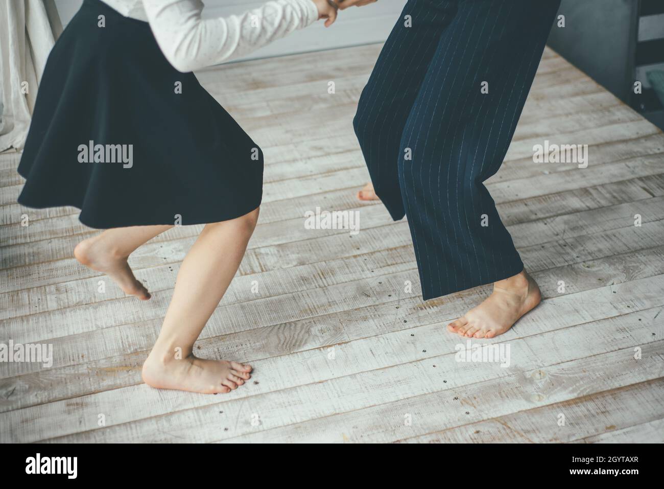 Pair of two girls dance barefoot on the white wooden floor and share ...