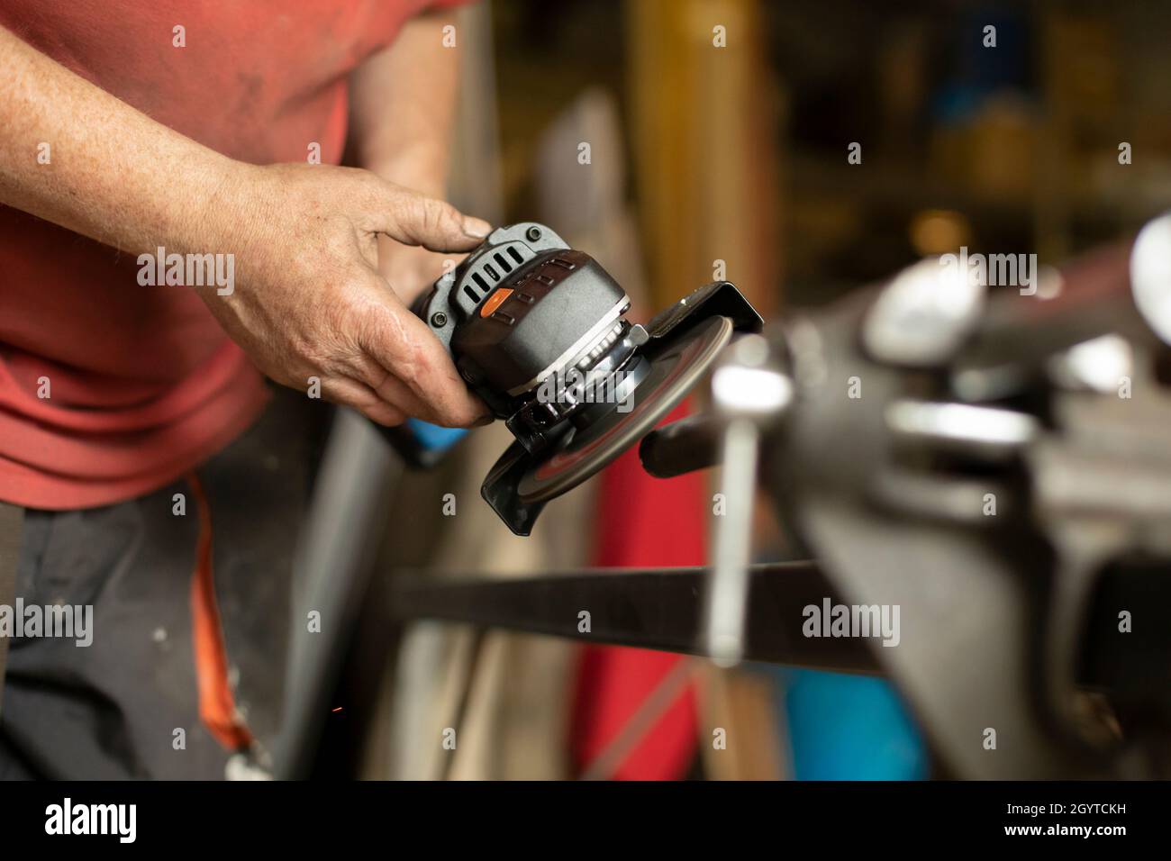 A man works in a garage. Making a product of steel. Rough work ...