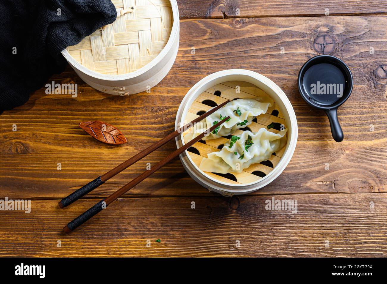 Chinese dumplings wooden steamer on wood background with soy and sticks ...