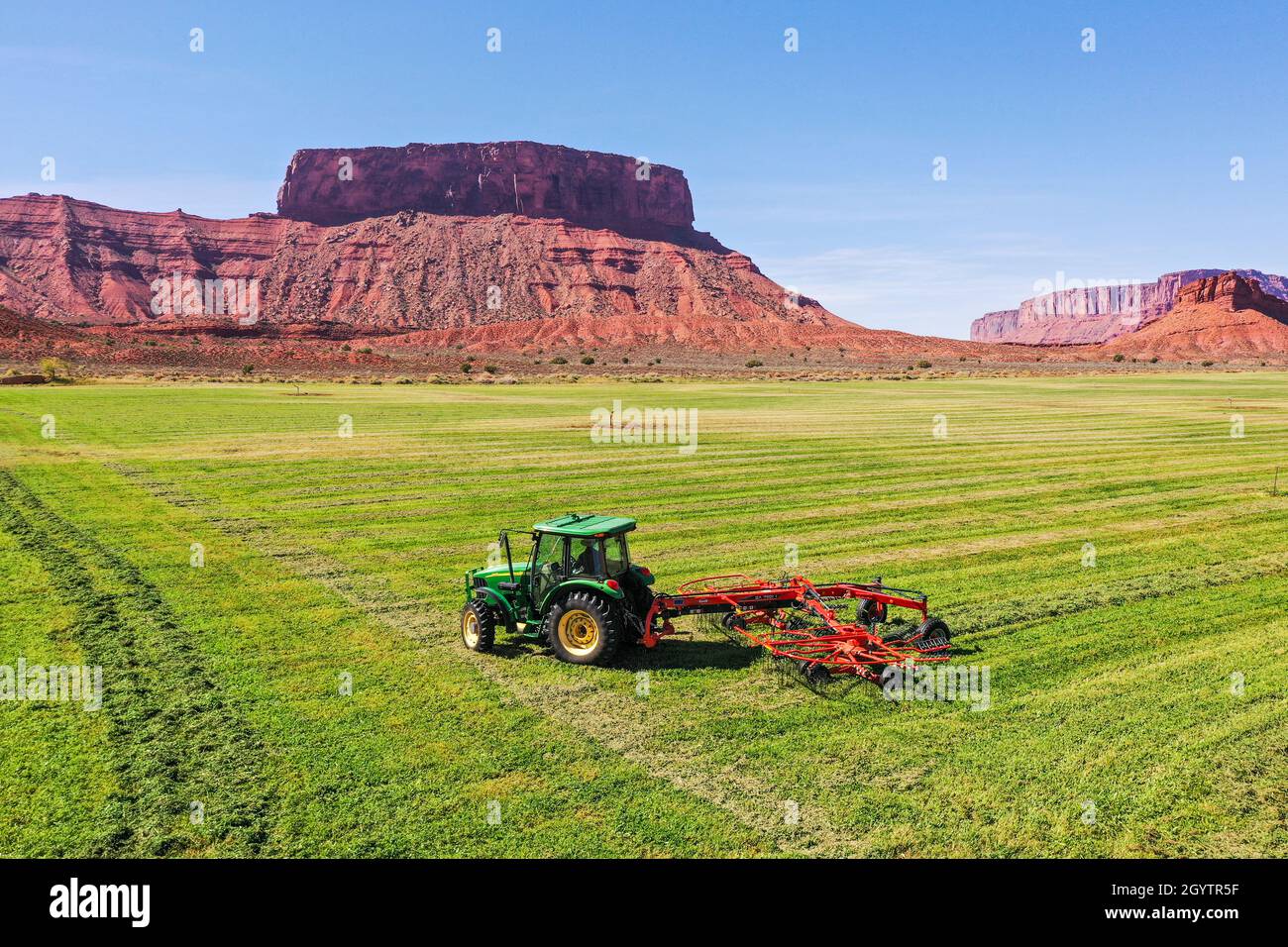 A rotary rake combining smaller windrows of hay into one larger row for ...