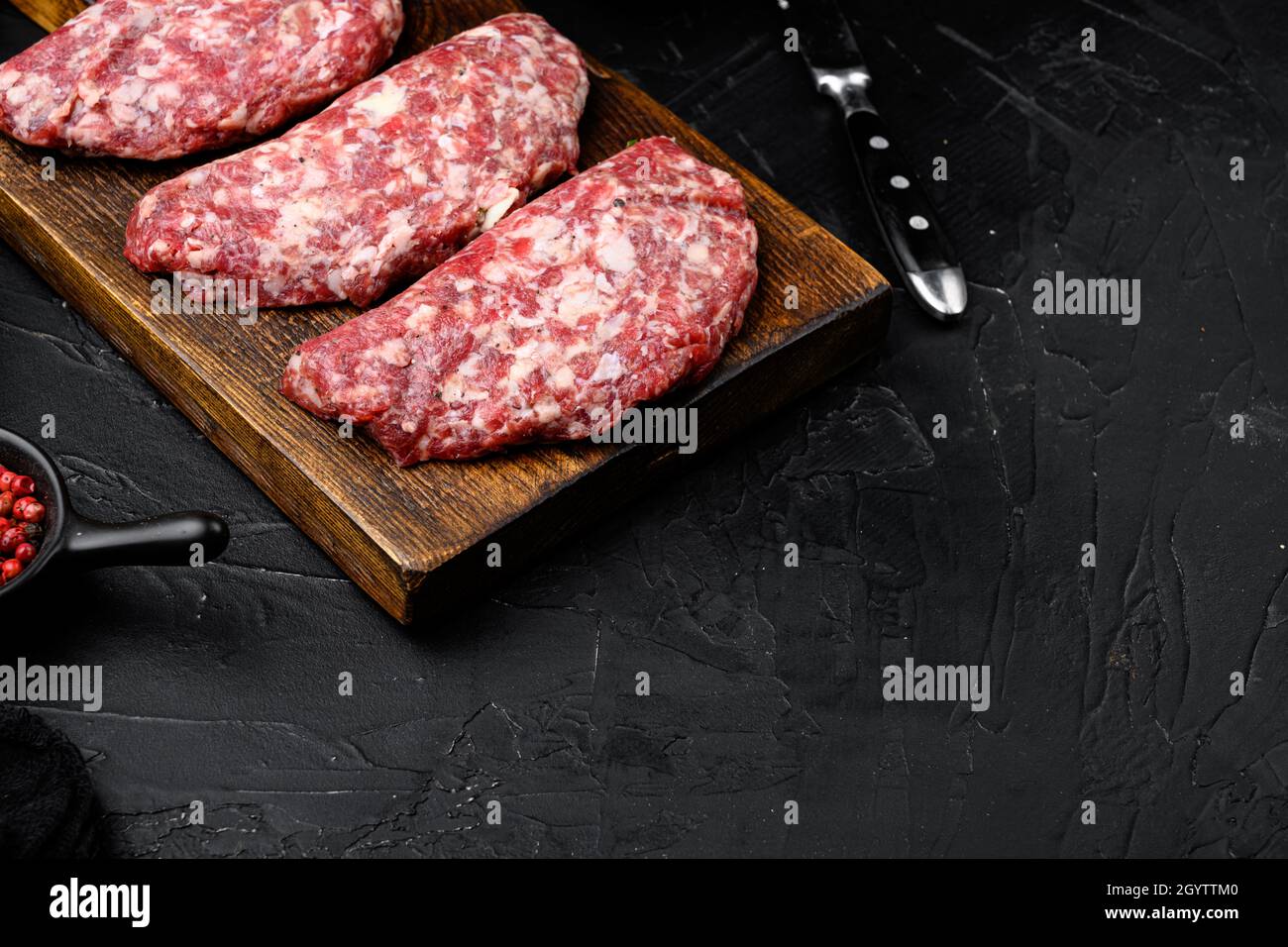 Raw beef patty set, on black dark stone table background, with copy ...