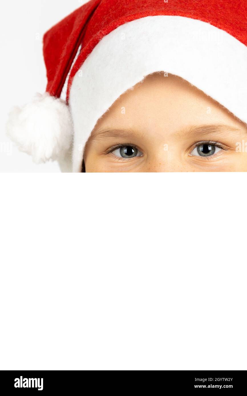 half face of child in Santa Claus hat is behind white blank card ...