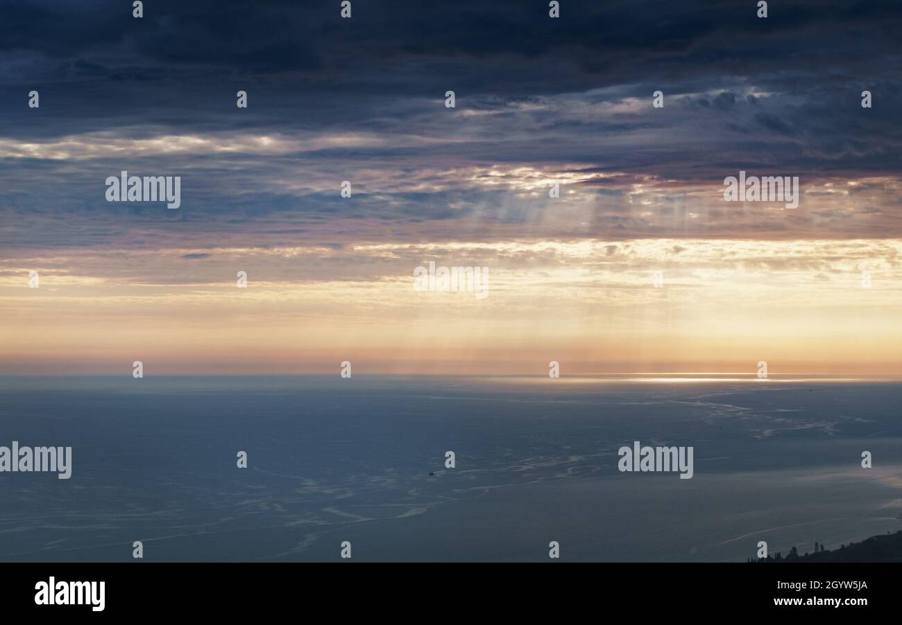 Thunderclouds over the sea at sunset disappearing into the horizon ...