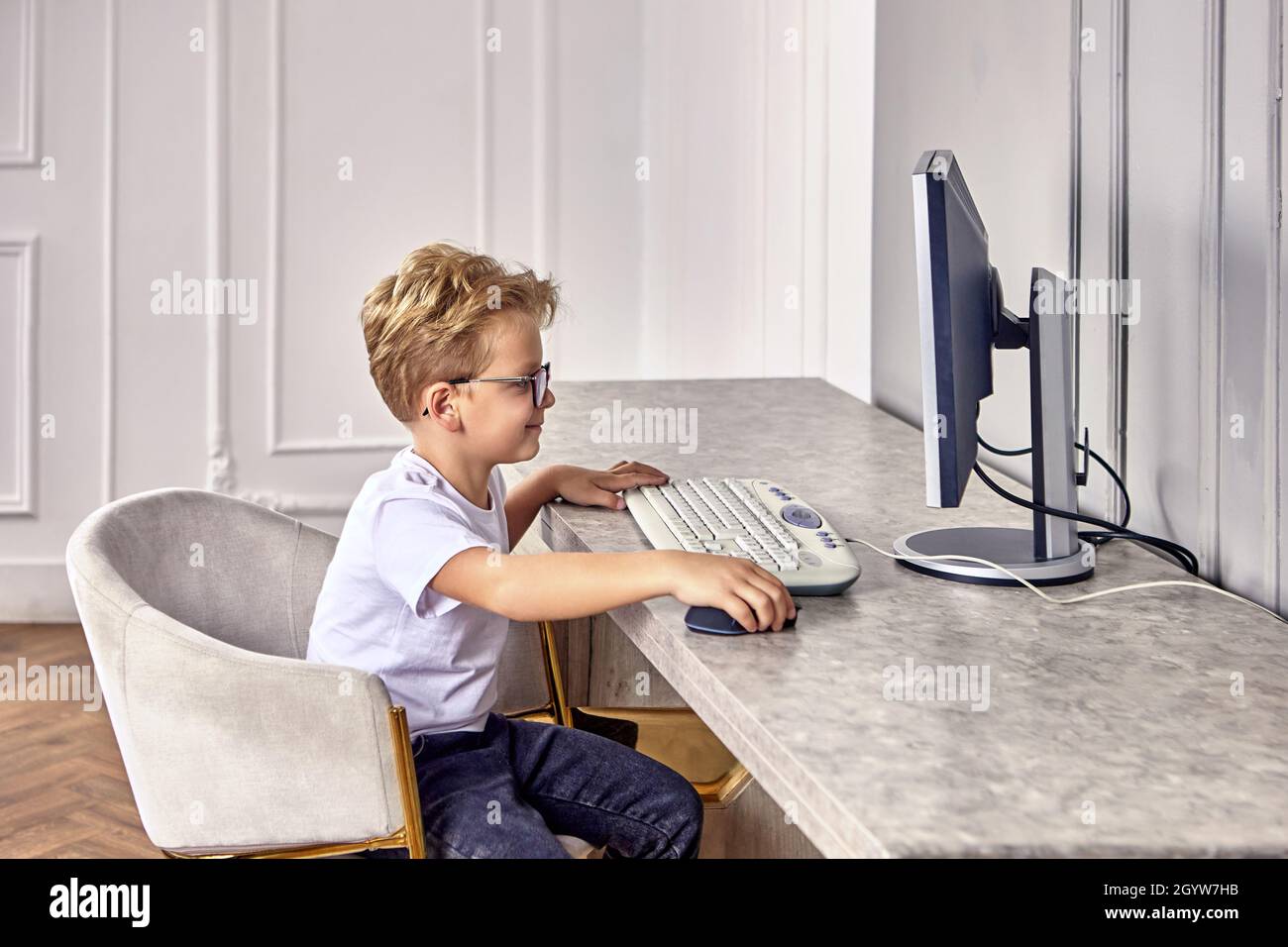 Happy european little boy in glasses sits behind computer Stock Photo ...