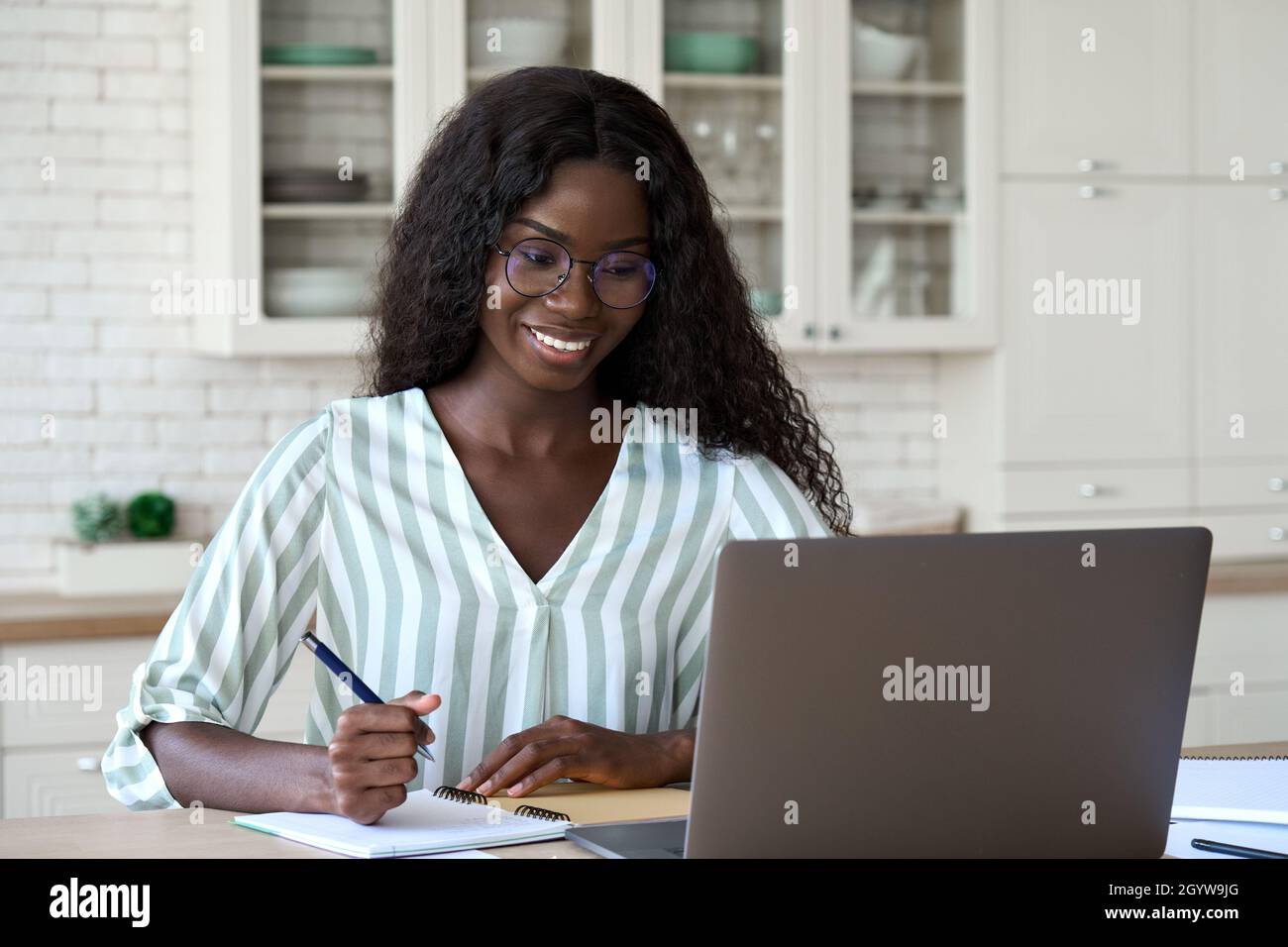 Happy black woman student learning at home looking at laptop watching ...