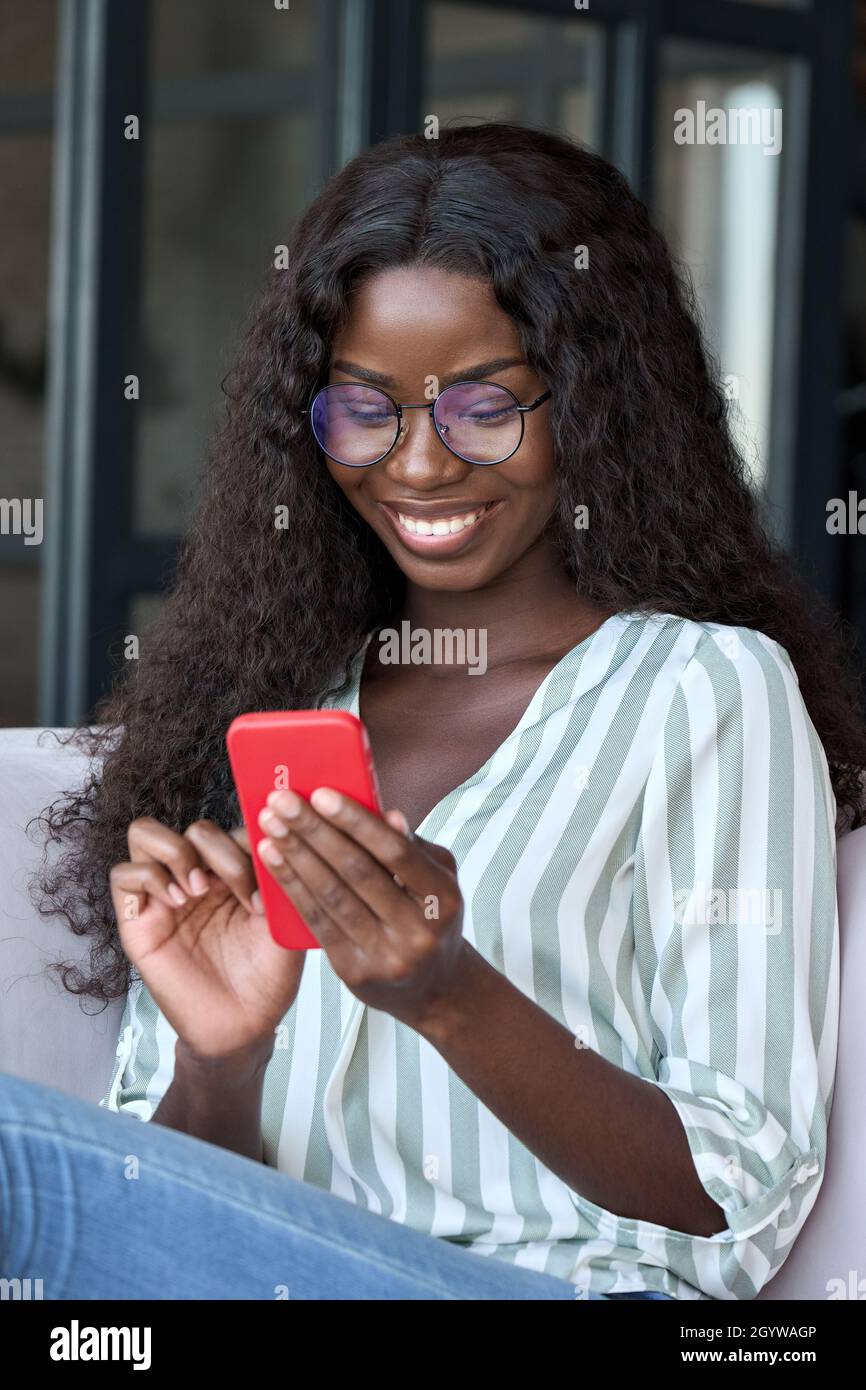 Young Happy Black African Woman Using Mobile App On Cell Phone Sitting