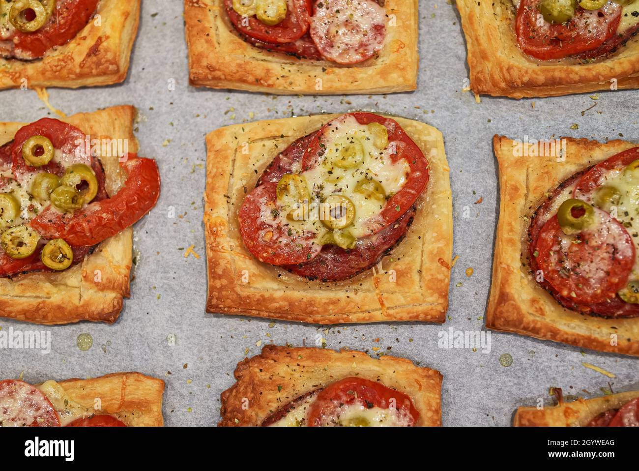 Baked square mini pizzas with salami, cheese, olives and tomato Stock ...