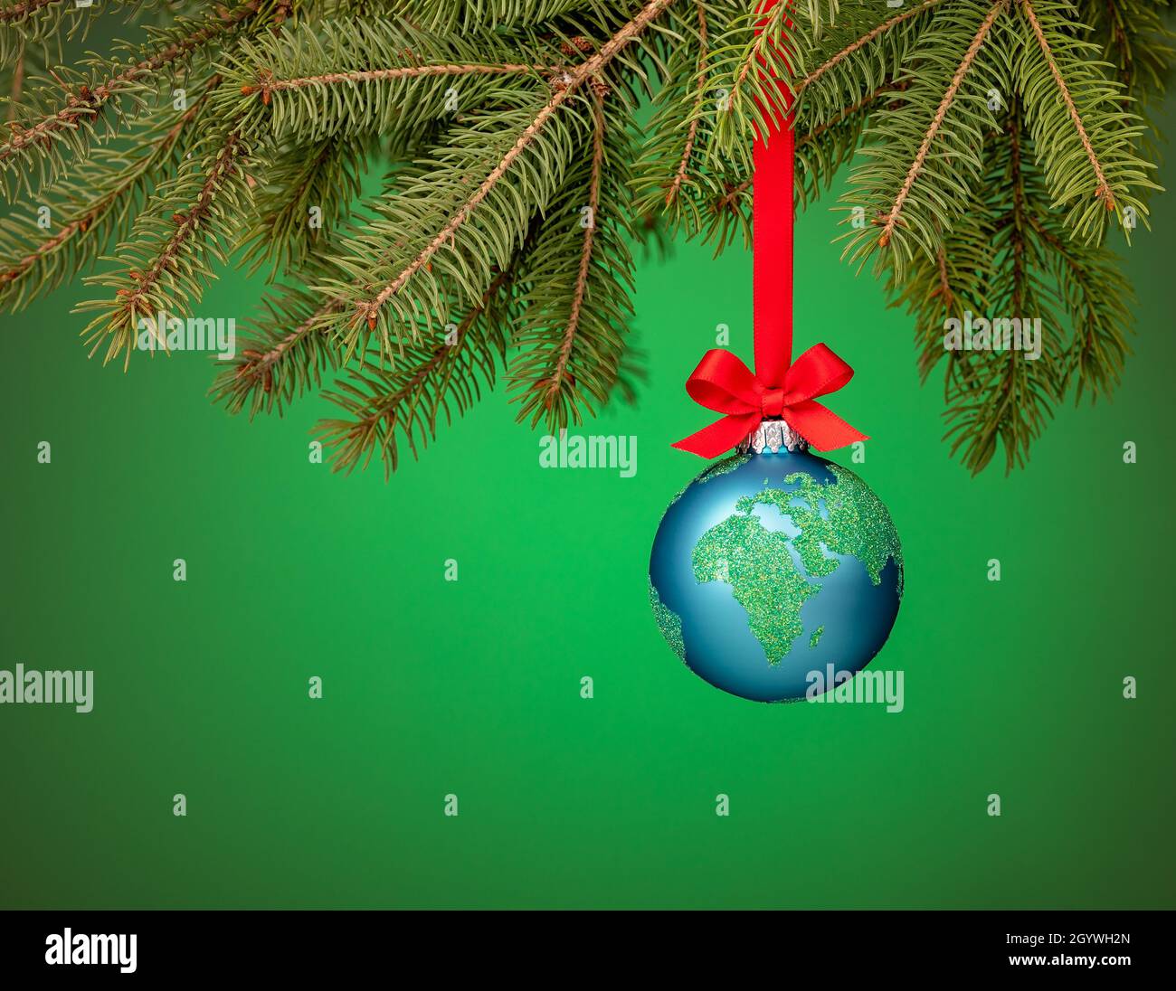 Globe christmas ornament hanging from a tree branch on green. Peace on ...