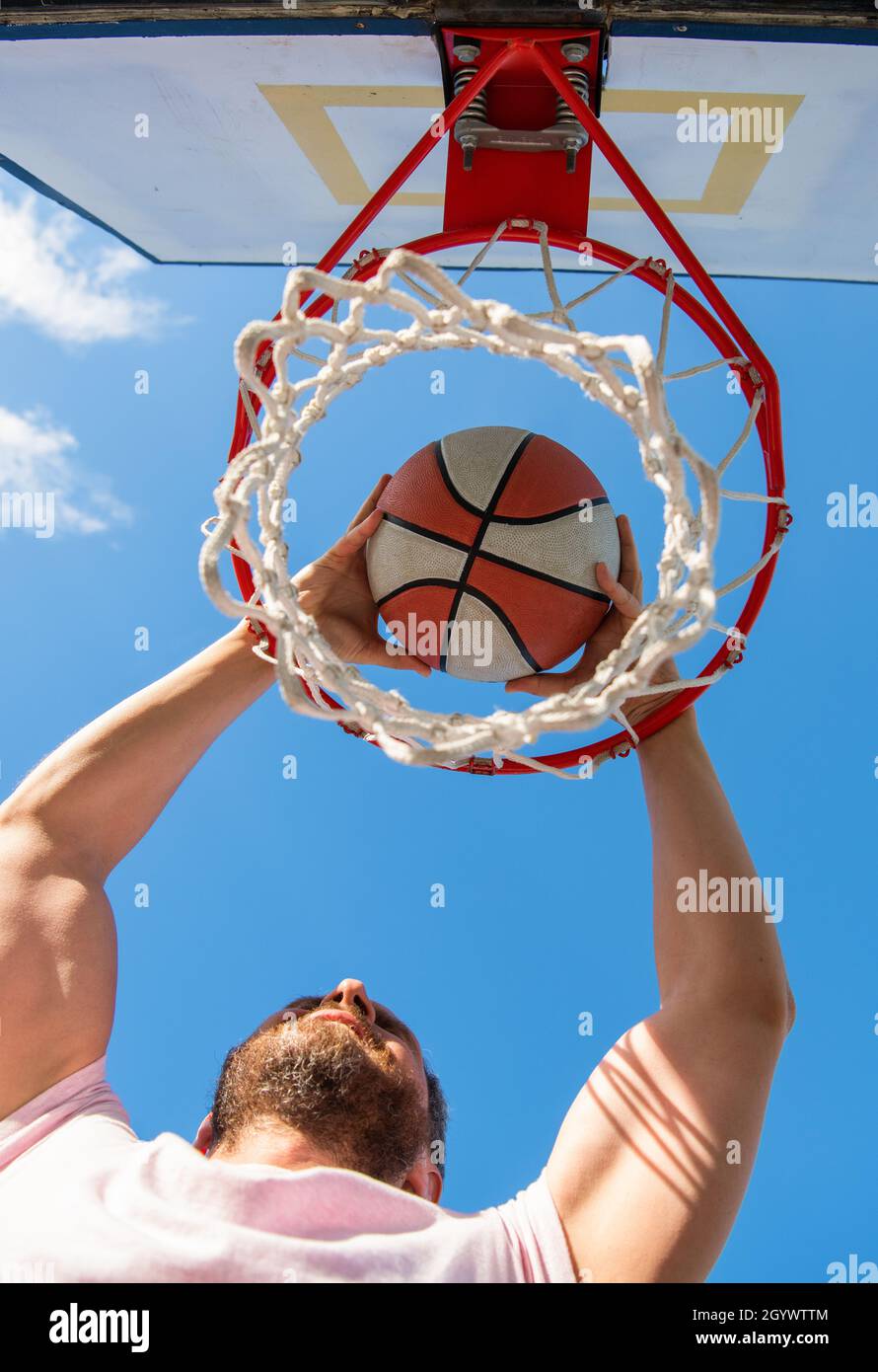man dunking basketball ball through net ring with hands, success Stock ...