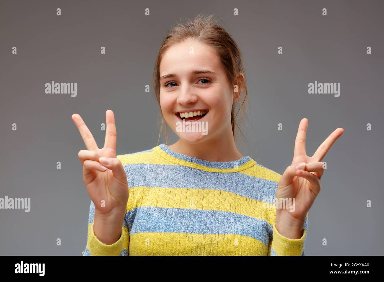I double won! portrait of smiling young woman making victory gesture ...