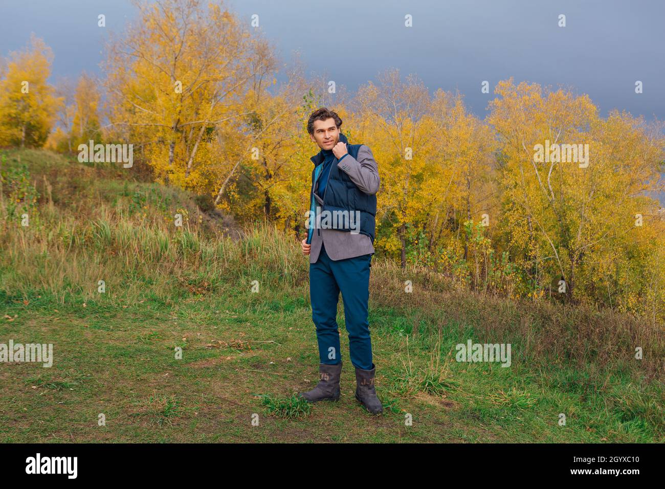 Tall handsome man walking outdoor in yellow autumn forest on the hill ...