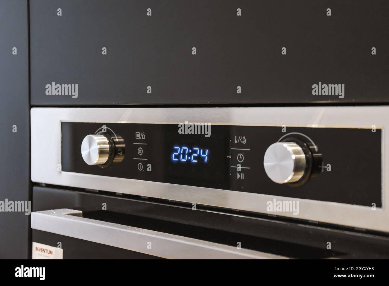 A closeup of controls from a modern stainless steel oven with timer ...