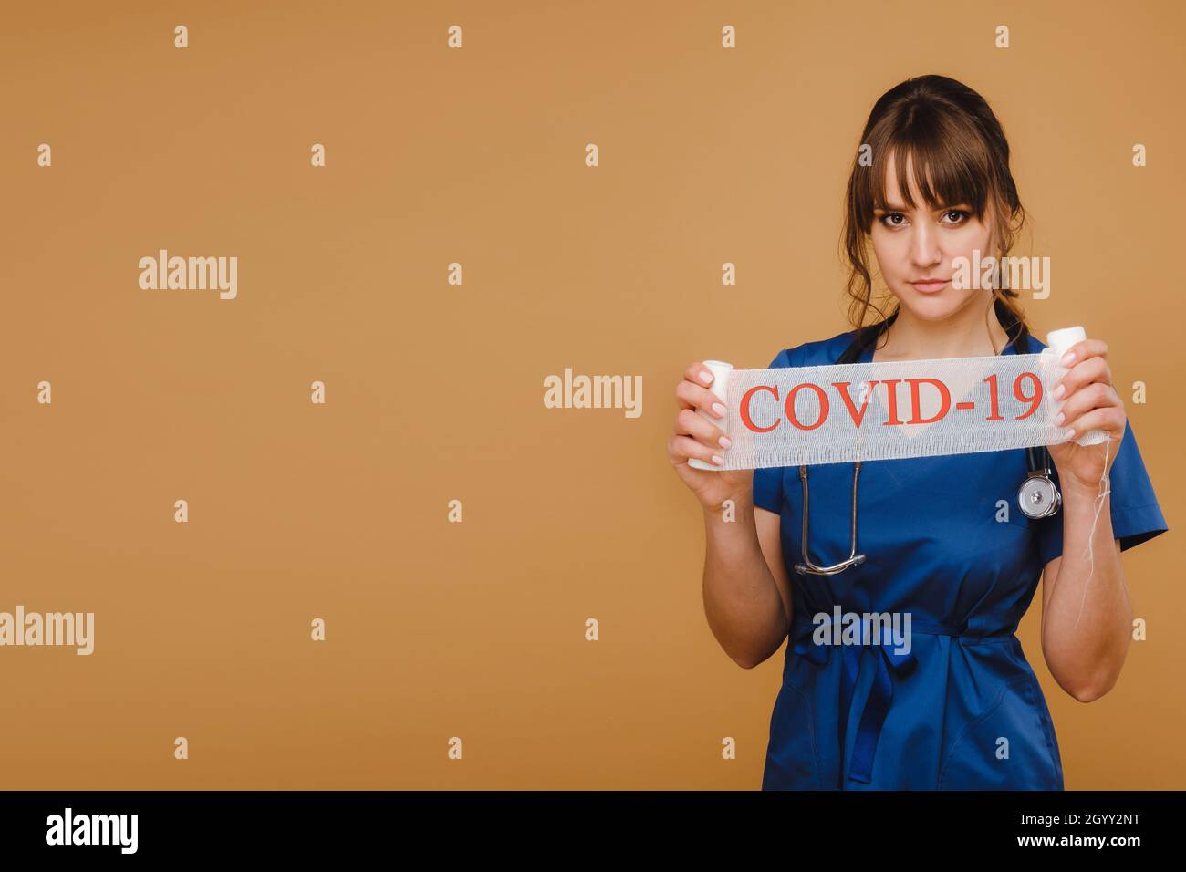 a doctor in a mask, gloves and with a stethoscope holds in his hands ...