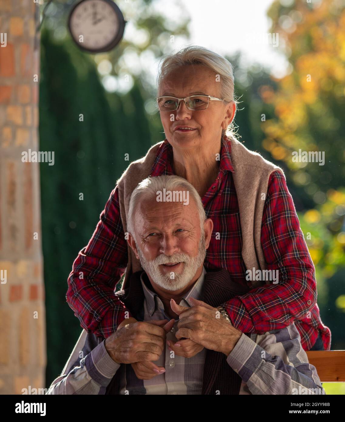 Senior man and woman hugging in garden on autumn sun Stock Photo - Alamy