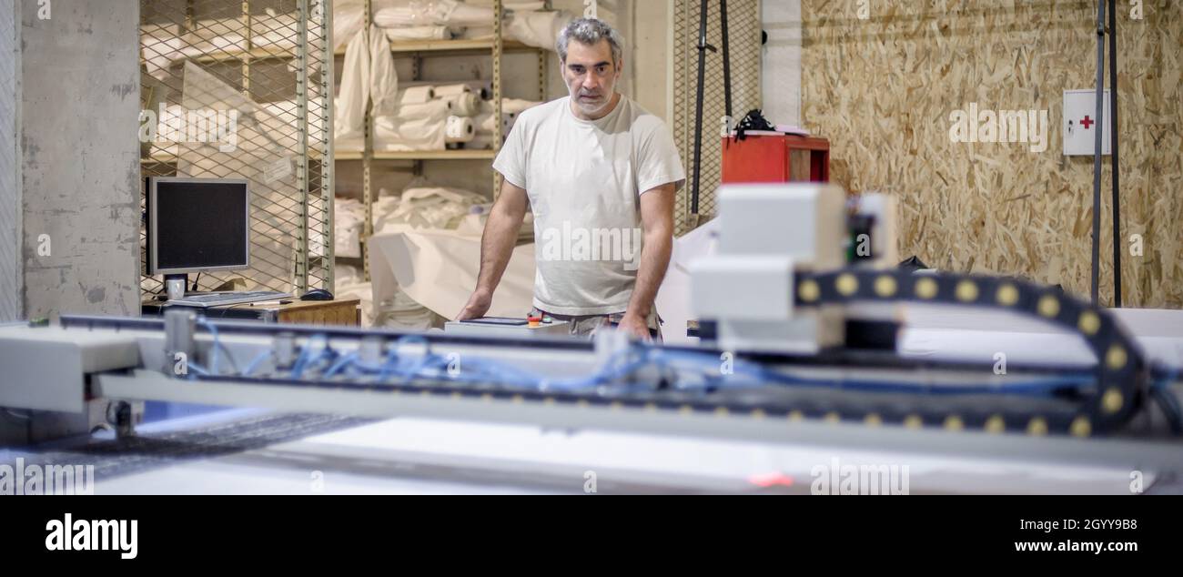 Factory worker technician works on large CNC digital cutter machine for ...