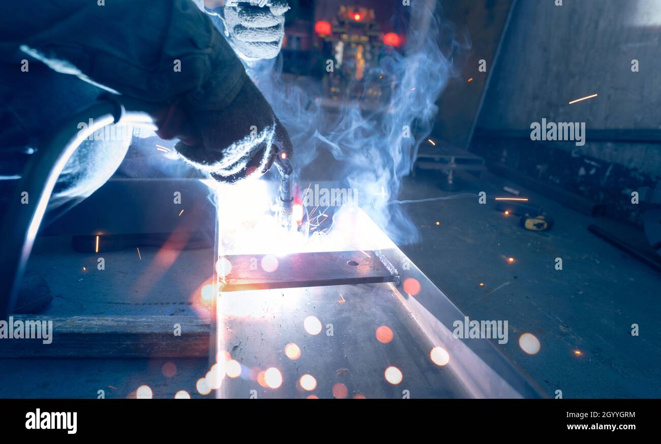Welder welding metal with argon arc welding machine and has welding ...