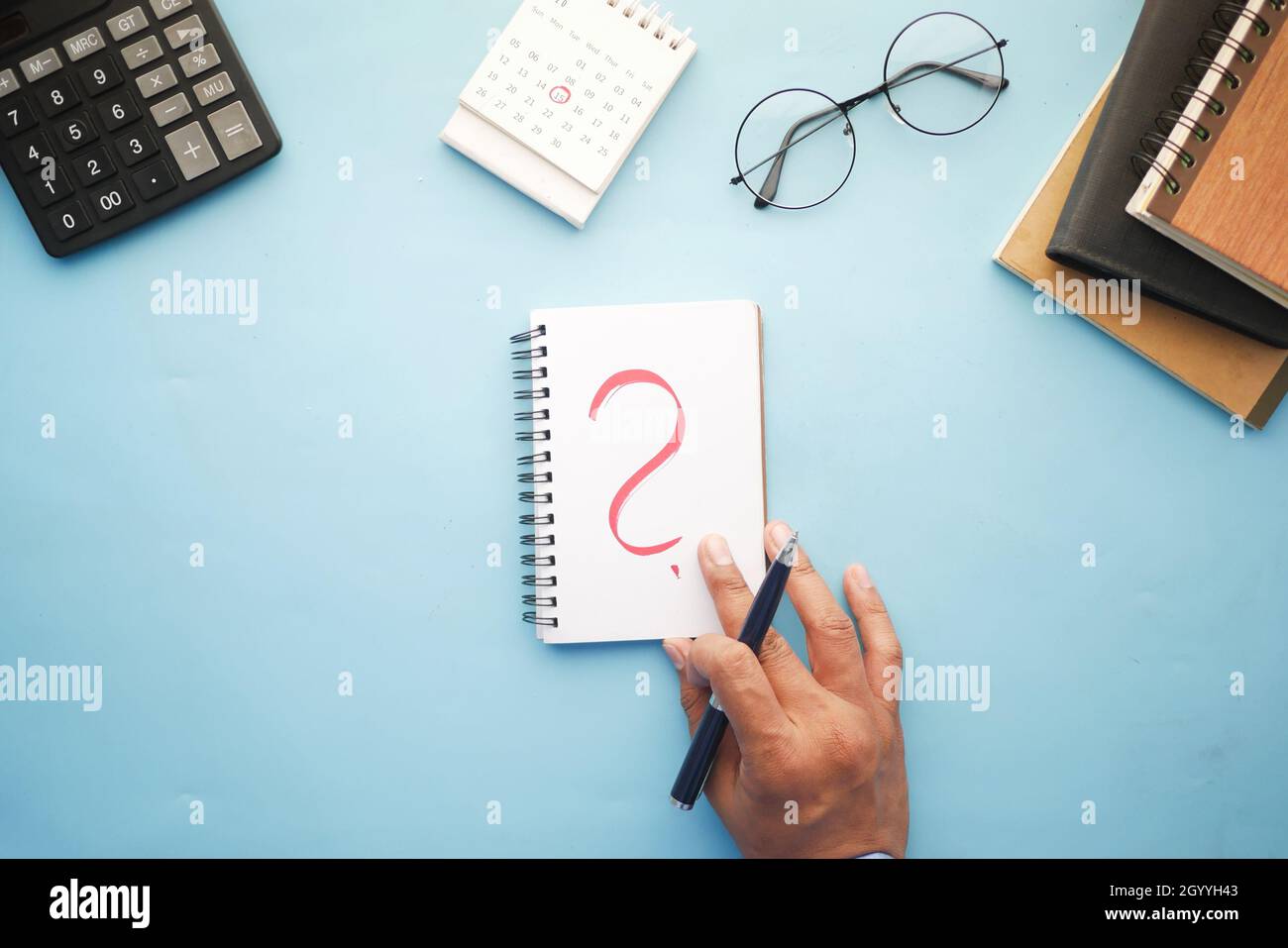 high angle view of hand drawing question mark on paper on office desk ...