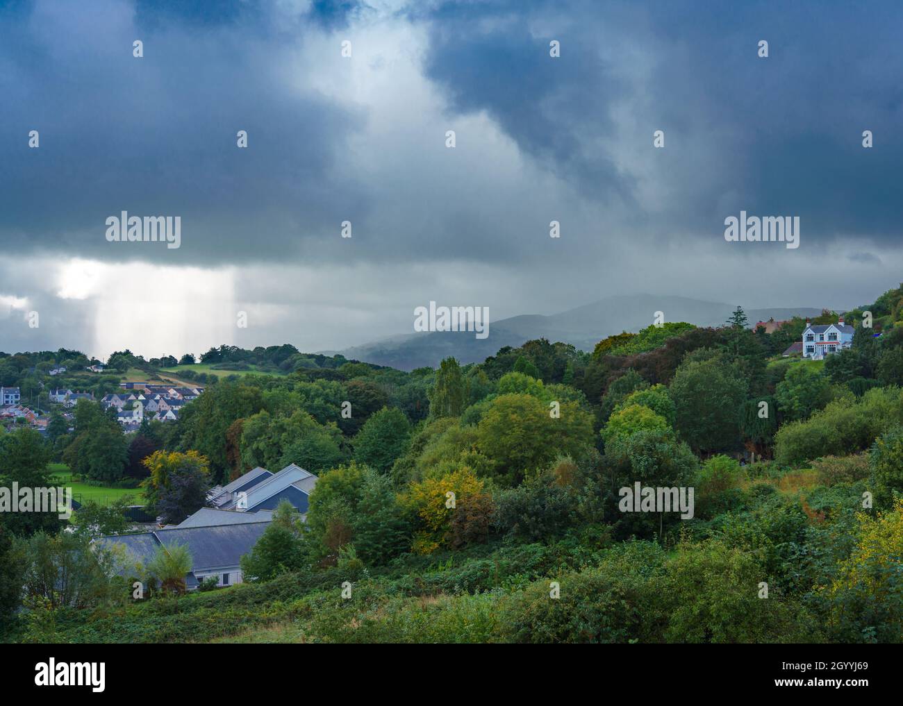a well of light appears through the distant raining storm clouds over ...