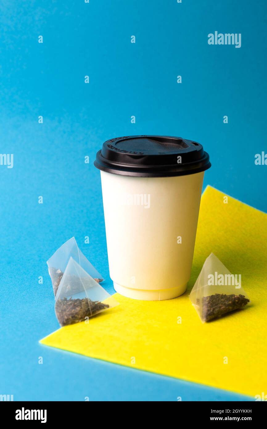 paper cup and tea bags on a yellow-blue background Stock Photo - Alamy