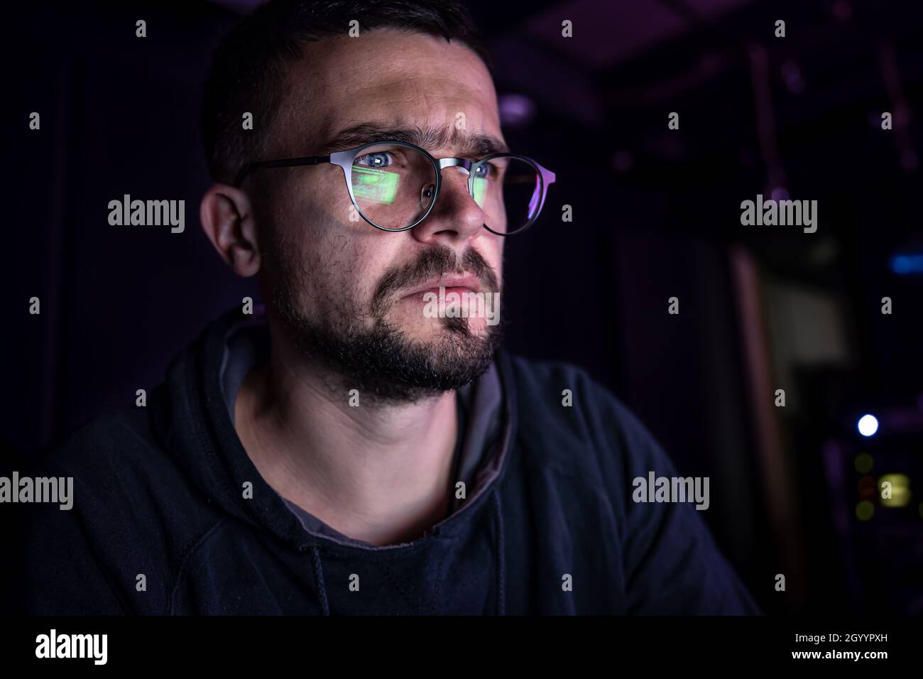 A man stares intently at a computer screen in the dark at night, copy ...