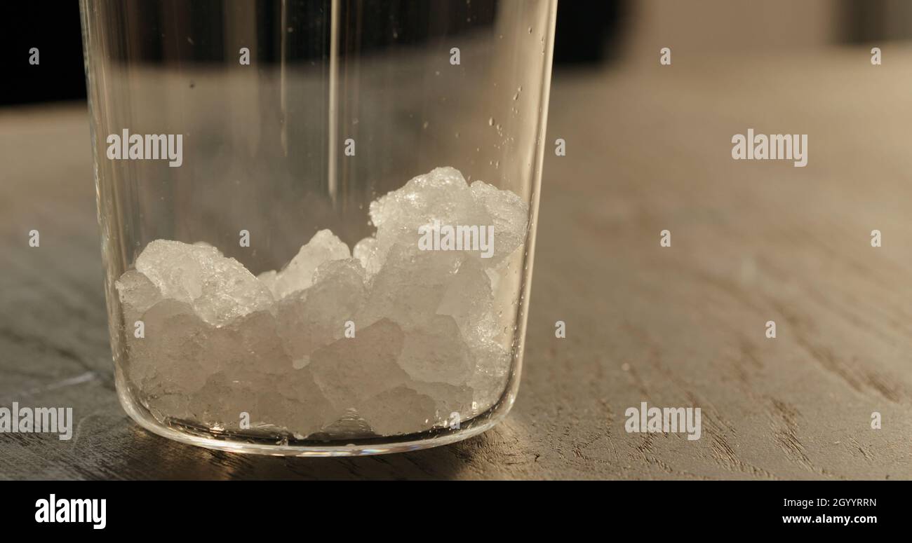 pour crushed ice in tumbler glass on oak table closeup , wide photo ...
