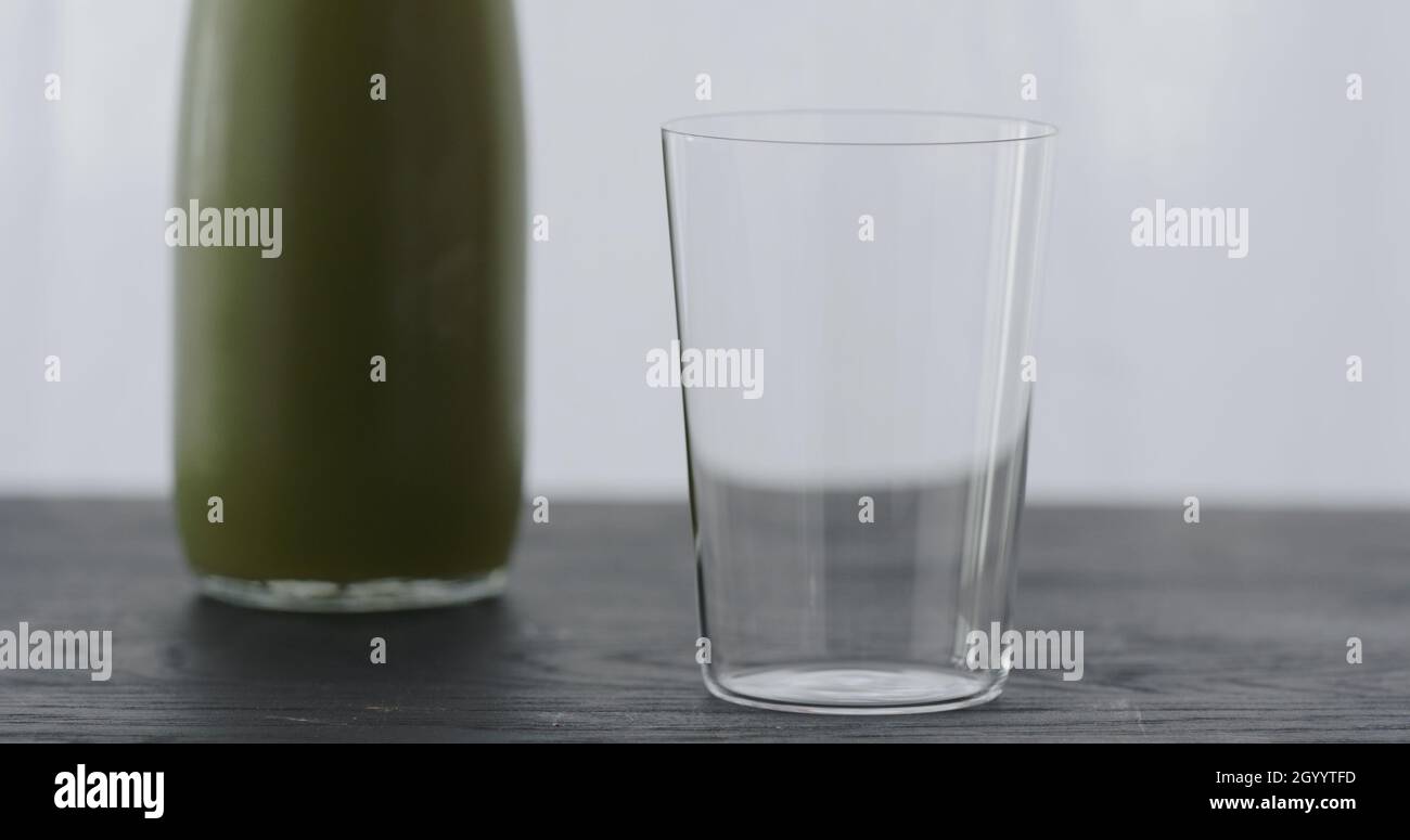green matcha drink in glass bottle on black oak table with copy space ...