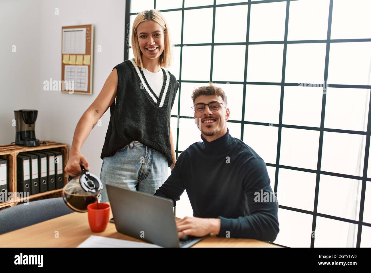 Two business workers smiling happy working and drinking coffee at the ...