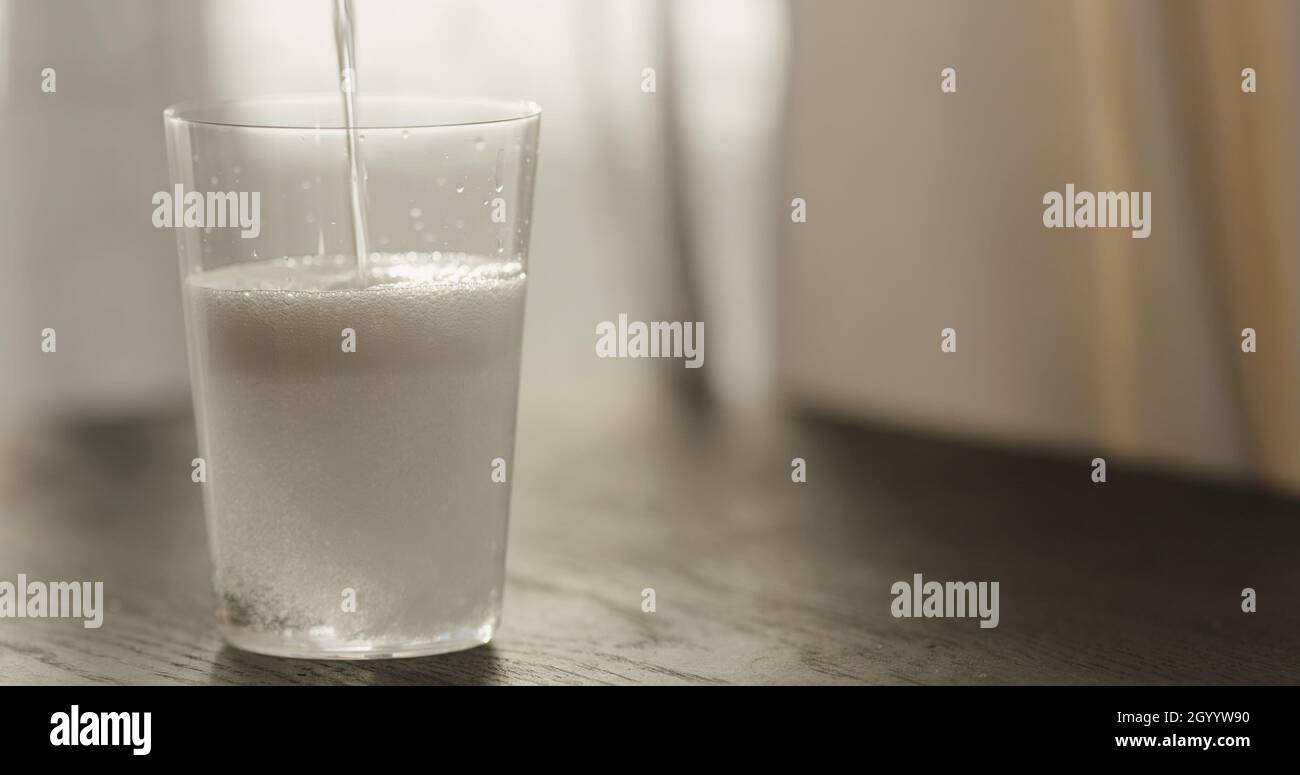 pour sparkling water in tumbler glass on black oak table with copy ...