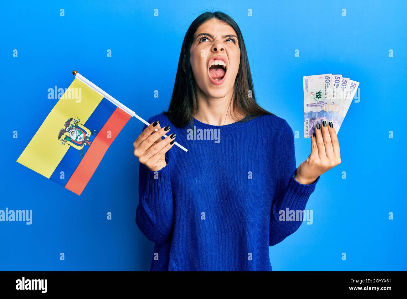 Young hispanic woman holding colombia flag and colombian pesos ...