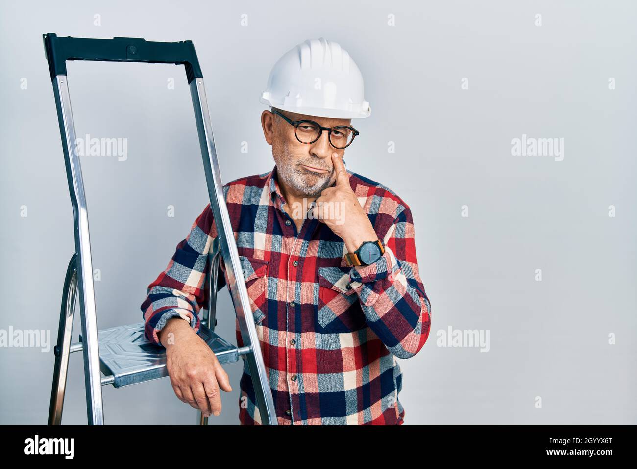 Handsome mature handyman close to construction stairs wearing hardhat ...