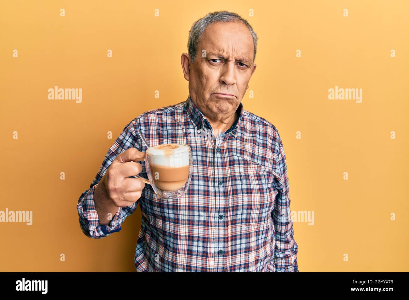 Handsome senior man with grey hair drinking a cup coffee depressed and ...