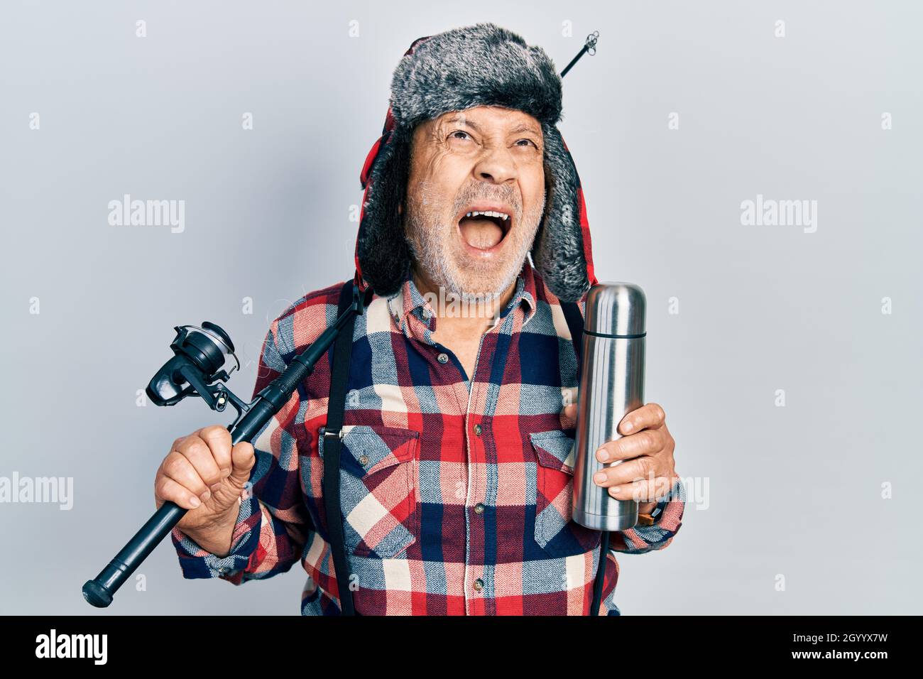 Handsome mature man wearing fisherman equipment and thermo angry and ...