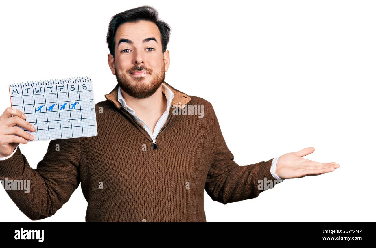 Young hispanic man holding travel calendar celebrating achievement with ...